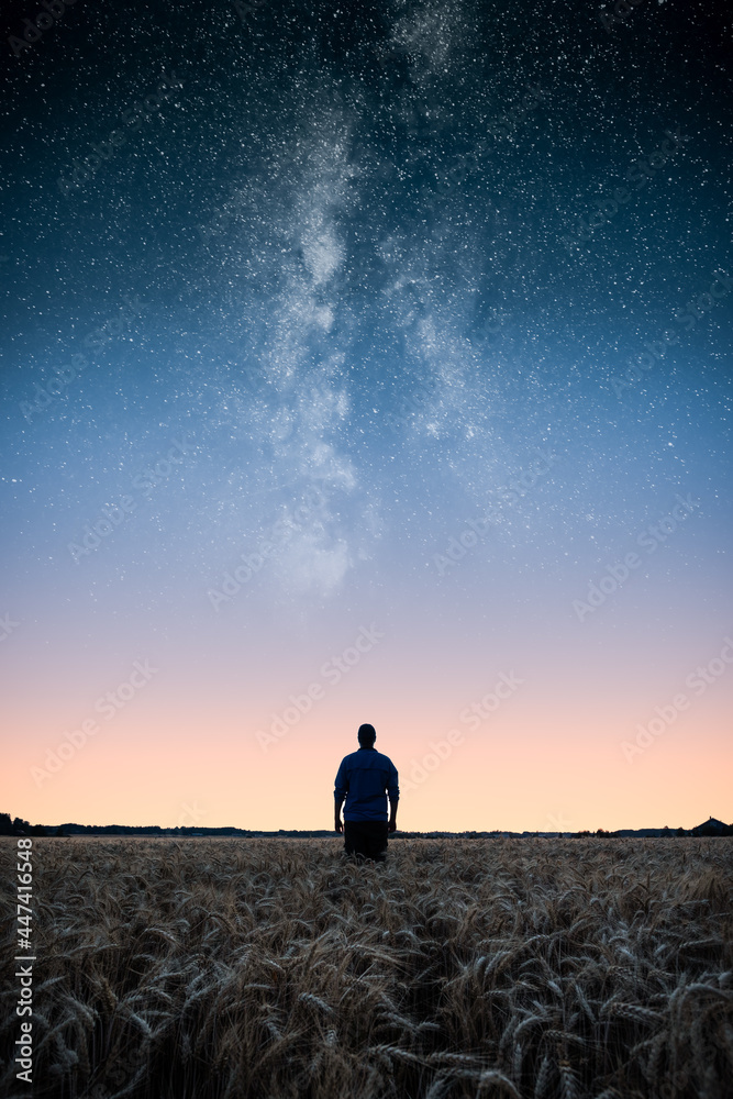 Man standing on wheat field under the stars of the milky way at night ...