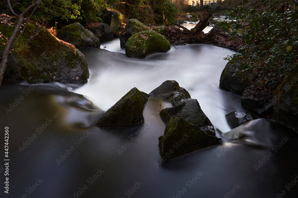 silky smooth watersurface and pitch black rocks in a river with many ...