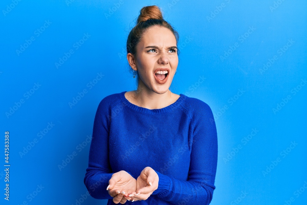 Young blonde woman holding hands together cupped, giving concept angry ...