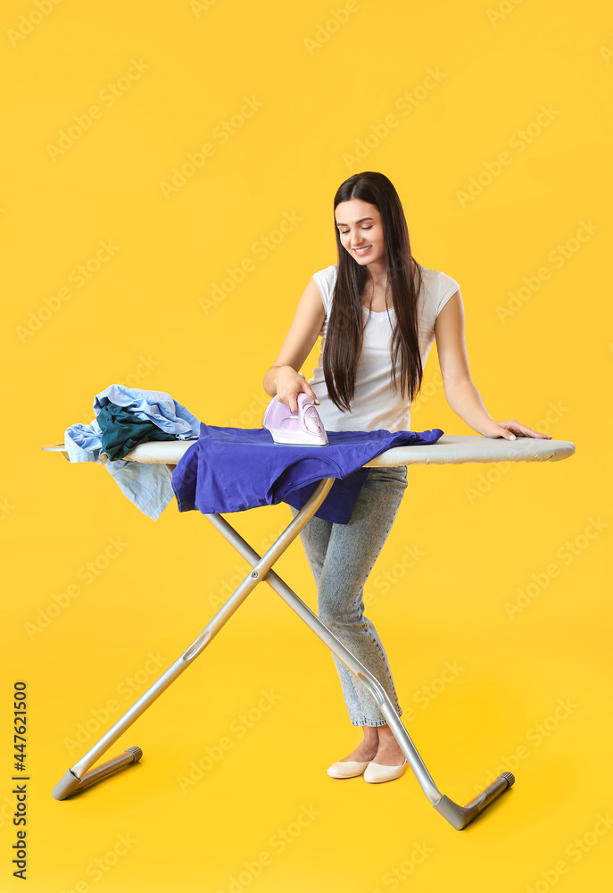 Young woman ironing clothes on color background Stock Photo | Adobe Stock