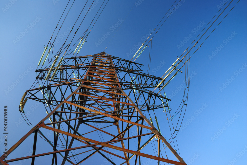 High voltage electrical Power lines and electric pylon against a blue ...