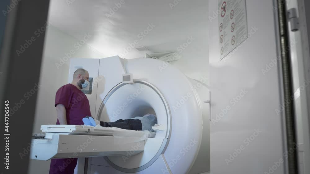 The doctor conducts an MRI or PET scan of a patient in a modern clinic ...
