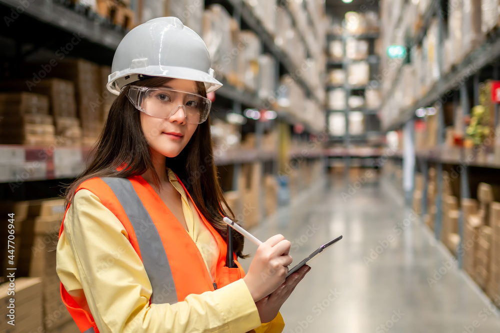 Female warehouse worker inspecting a warehouse in a factory. Wear a ...