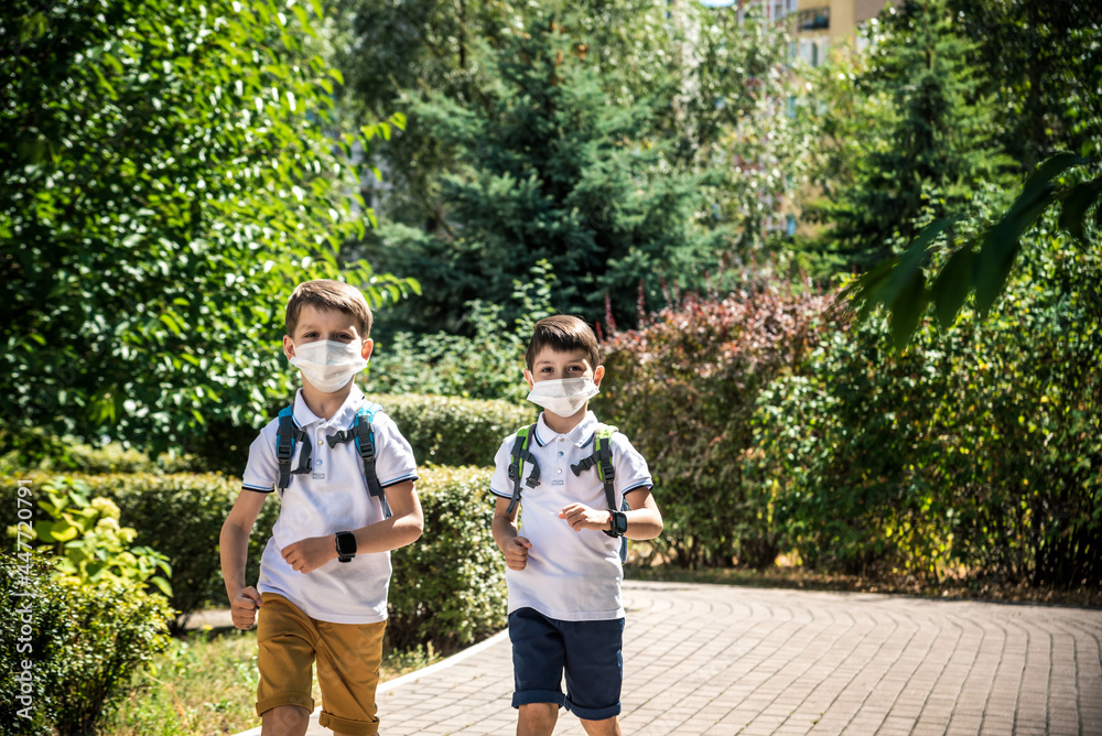 Happy schoolchildren with face masks run from the joy of returning to ...