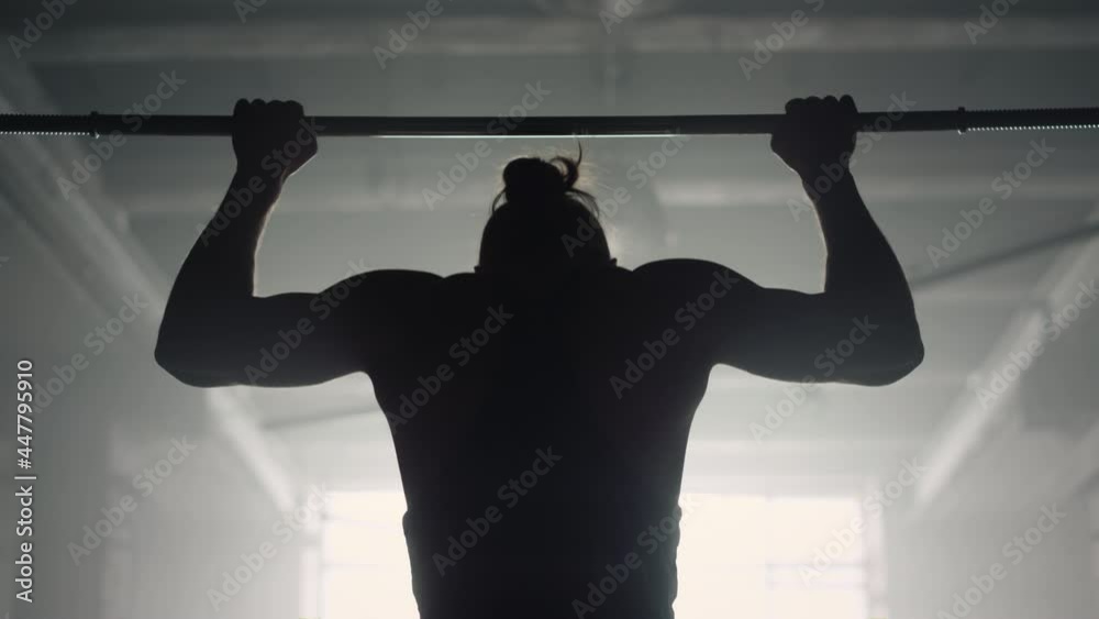 Man doing wide grip pull ups on bar. Athlete pumping arm muscles with ...
