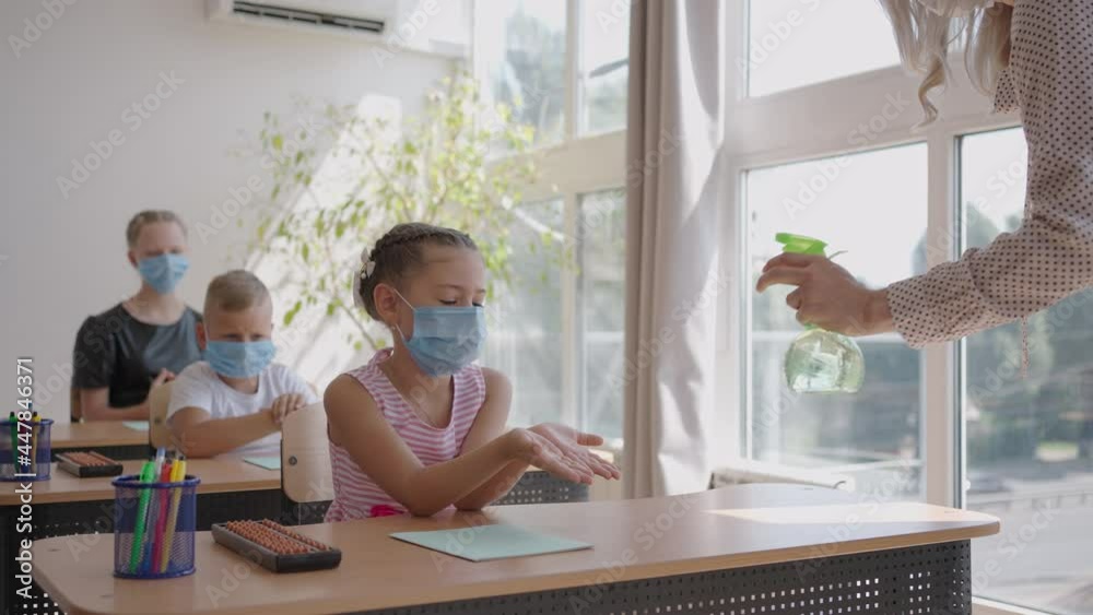 The teacher treats the hands of an antiseptic girl in the classroom at ...