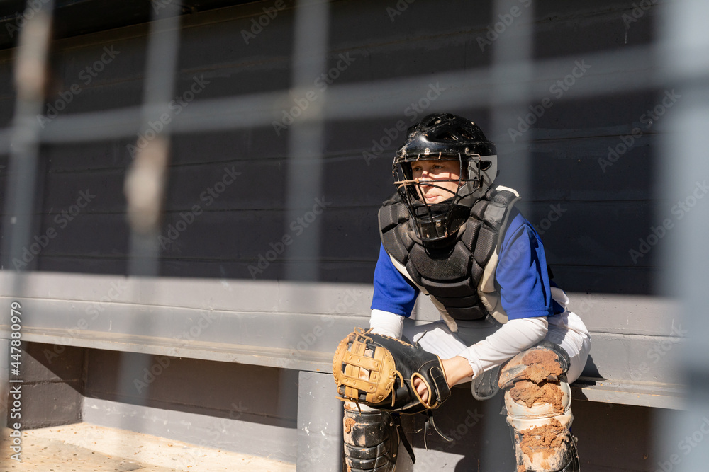 Caucasian female baseball player sitting on bench wearing catcher's ...