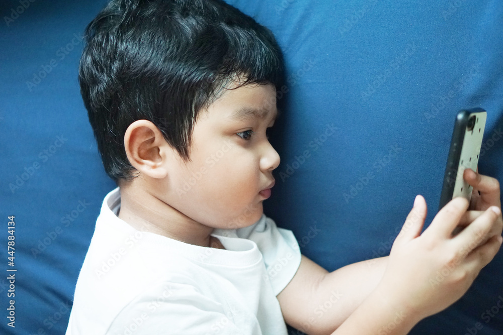 Cute little Asian 4 year old baby boy child watching a video from smart ...