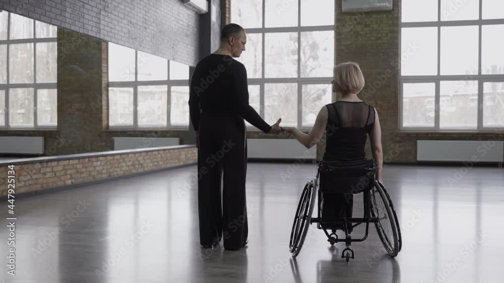 Rear view of man and disabled woman ballroom dancers holding hands and ...