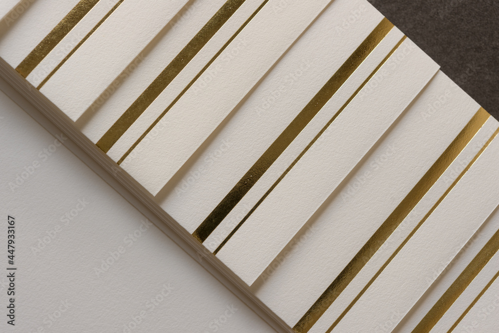 stack of brochure paper with gold trim border under soft moody ambient ...
