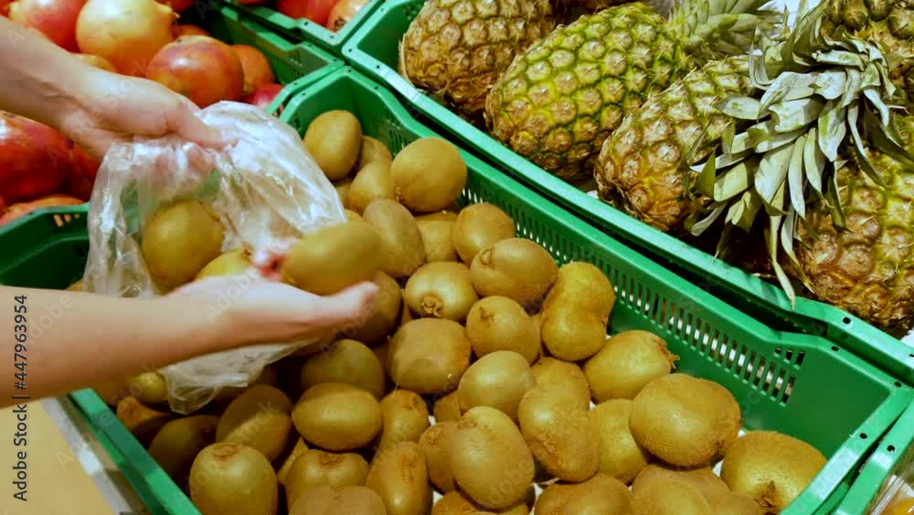 Buyer takes kiwi fruits in packet. Girl takes fresh kiwi fruits from ...