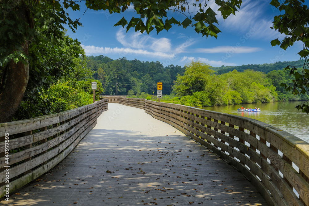 a long winding boardwalk along the river with a wooden rail along the ...