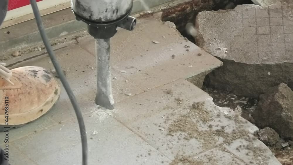 SLOW MOTION close up of a Pneumatic jackhammer breaking a paved floor ...