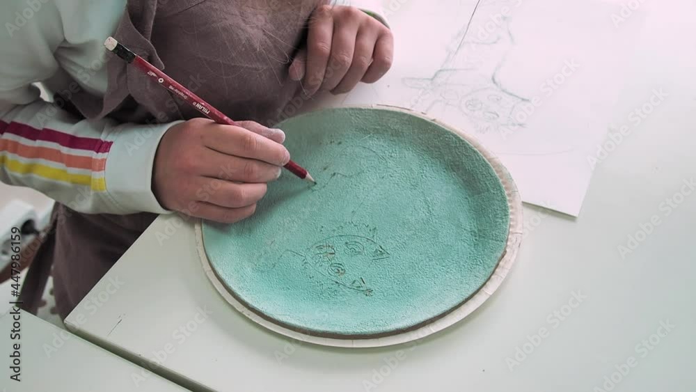 girl painting with pencil on colored clay pottery cup in ceramic ...