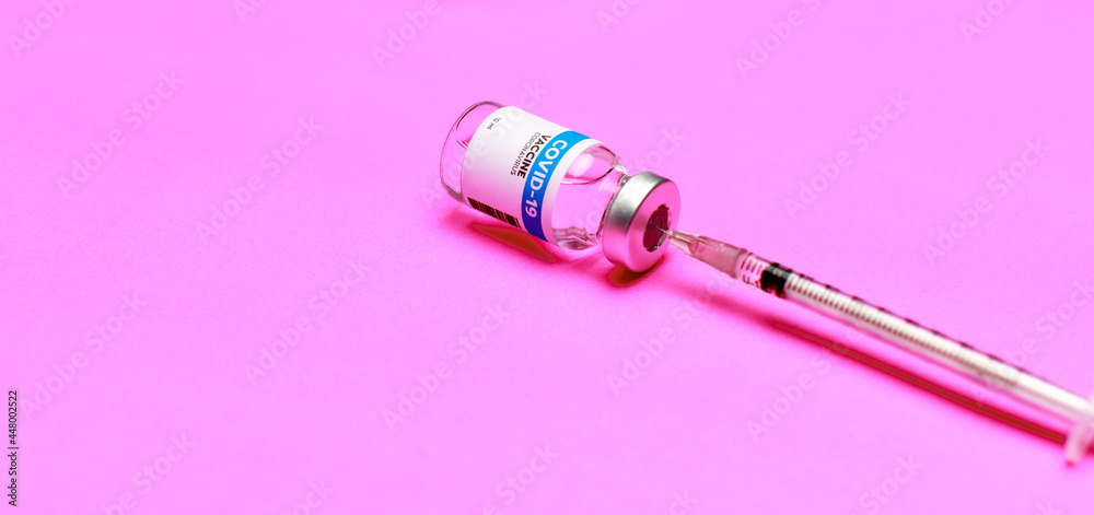 Medical syringe with needle inserted into sealed glass bottles of covid ...