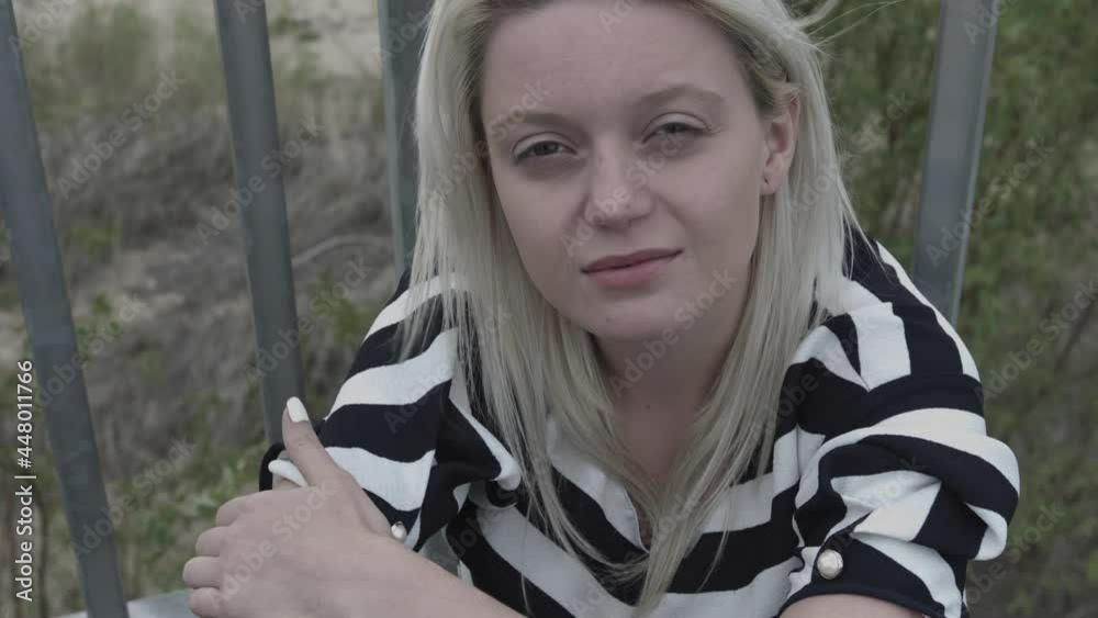 An ill woman sitting alone outside in a wind weather. A sad woman ...
