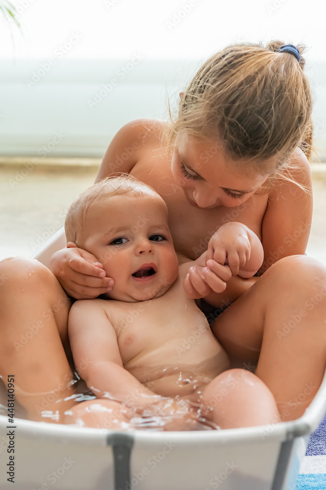 Caucasian girl bathing with her baby brother inside a portable bathtub Pepe Quilez Foto Poster Wandbilder bei EuroPosters