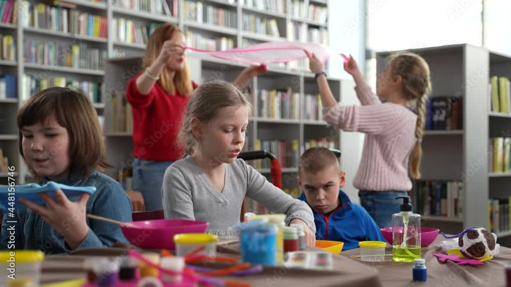 Video „Cheerful female teacher and girl inflating slime bubble, boy ...