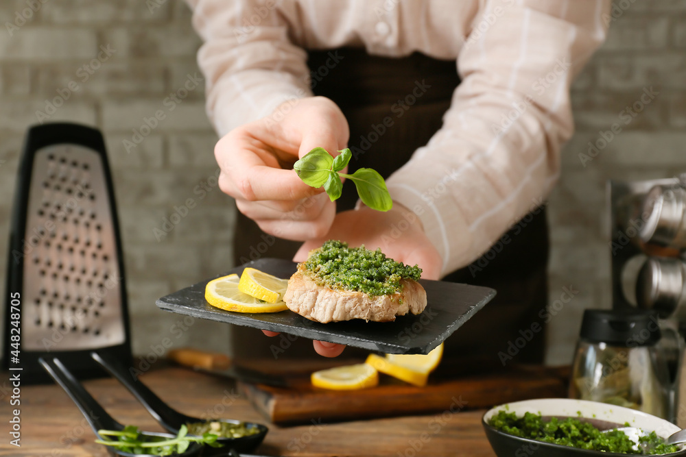 Woman decorating steak with pesto sauce in kitchen Stock Photo | Adobe ...