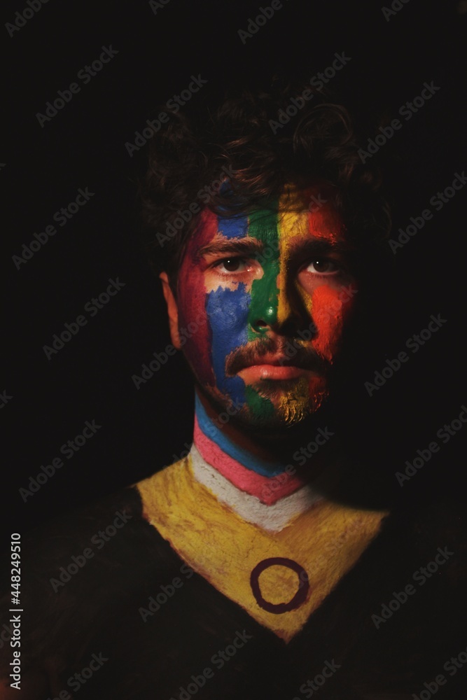 Portrait of young man face painted as lgbtq progress pride flag with ...