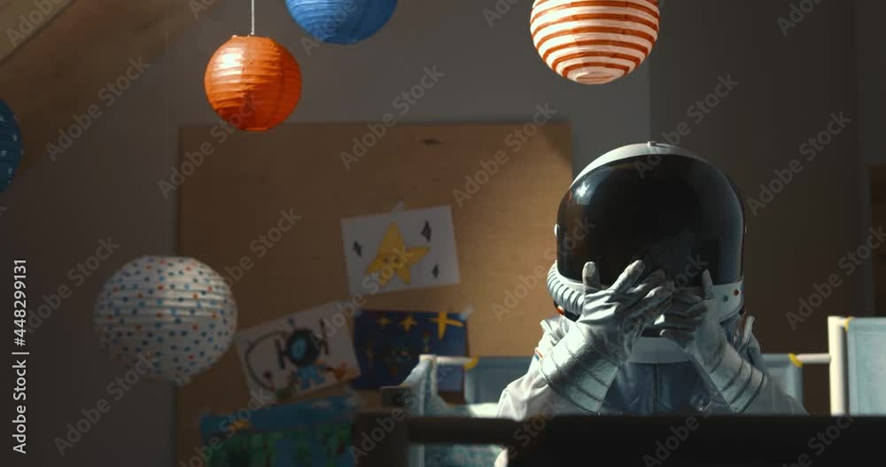 Dreaming about space travel. Little astronaut child sits on bed going ...