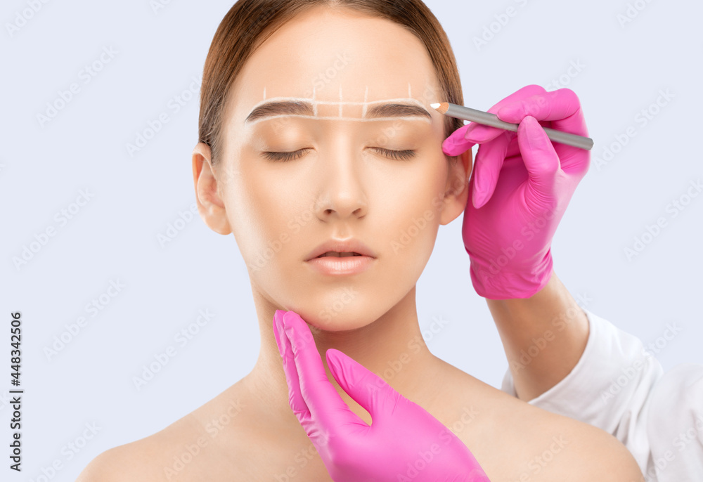 Make-up artist makes markings with white pencil for eyebrow and paints ...