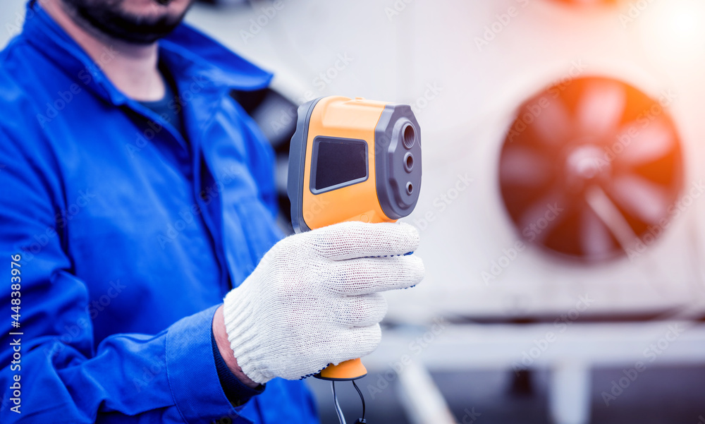 Technician uses a thermal imaging infrared thermometer to check the ...
