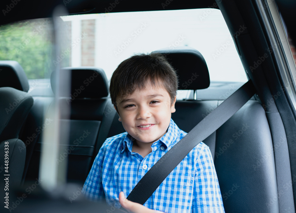 Cinematic portrait boy siting in safety car seat looking at camera with ...