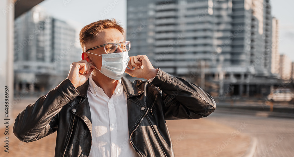 Handsome man putting on a medical protective mask on his face with ...