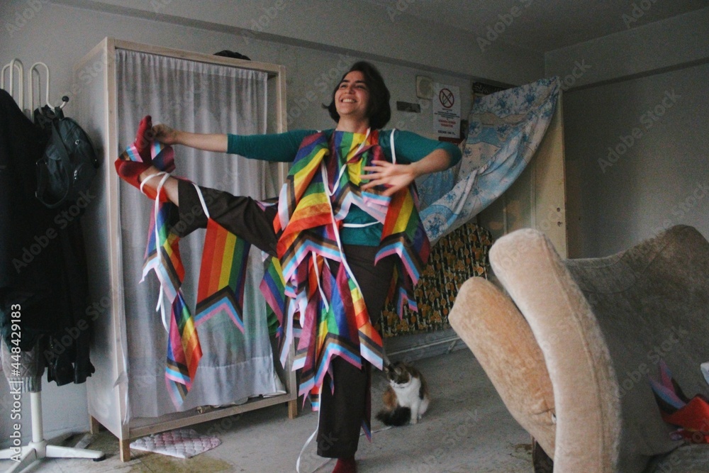 Portrait of Young woman doing yoga poses at home with lgbtq pride flags ...