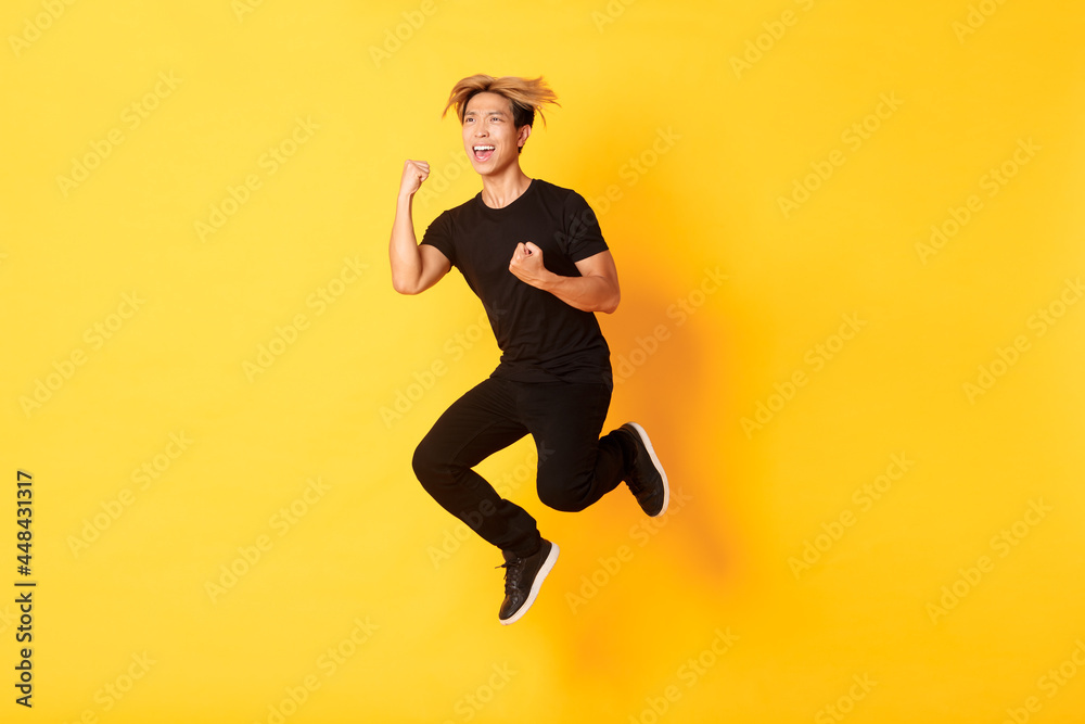 Full-length of happy attractive asian guy in black clothes jumping and ...