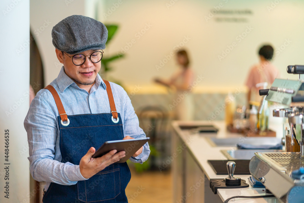 Asian man coffee shop manager walking behind bar counter working on ...
