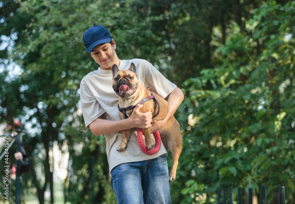 Teenager hugs his red french bulldog outside. Boy walking with cute ...