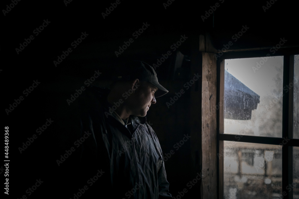 Silhouette of a suspicious strange man looking out the window in a ...