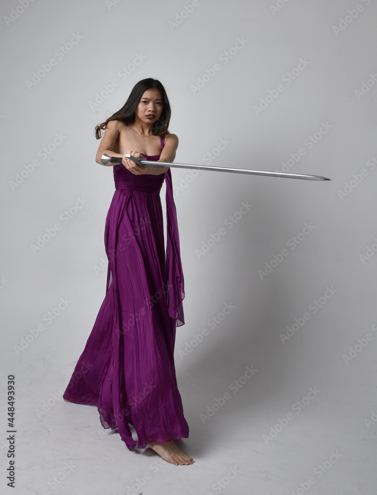 Full Length Portrait Of Pretty Brunette Asian Girl Wearing Purple Flowing Gown Sitting Pose