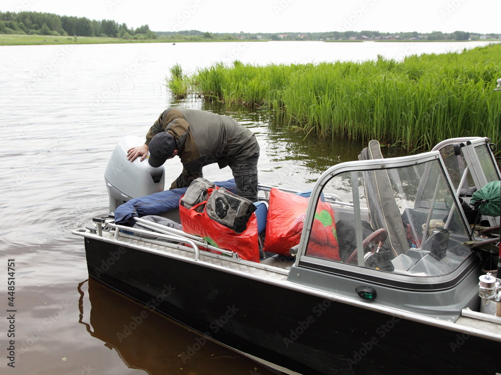 Boater man repairs the 50 hp four stroke outboard motor on transom of ...