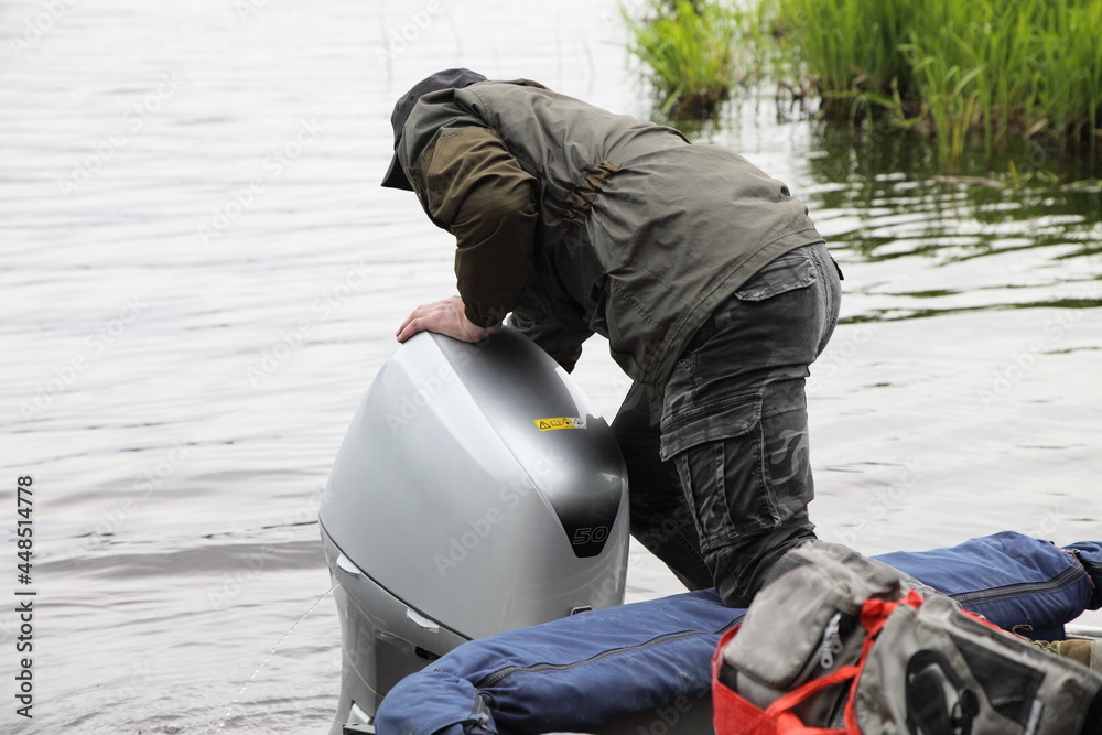 Boater man hands looking on the the gray hood of a 50 hp four stroke ...
