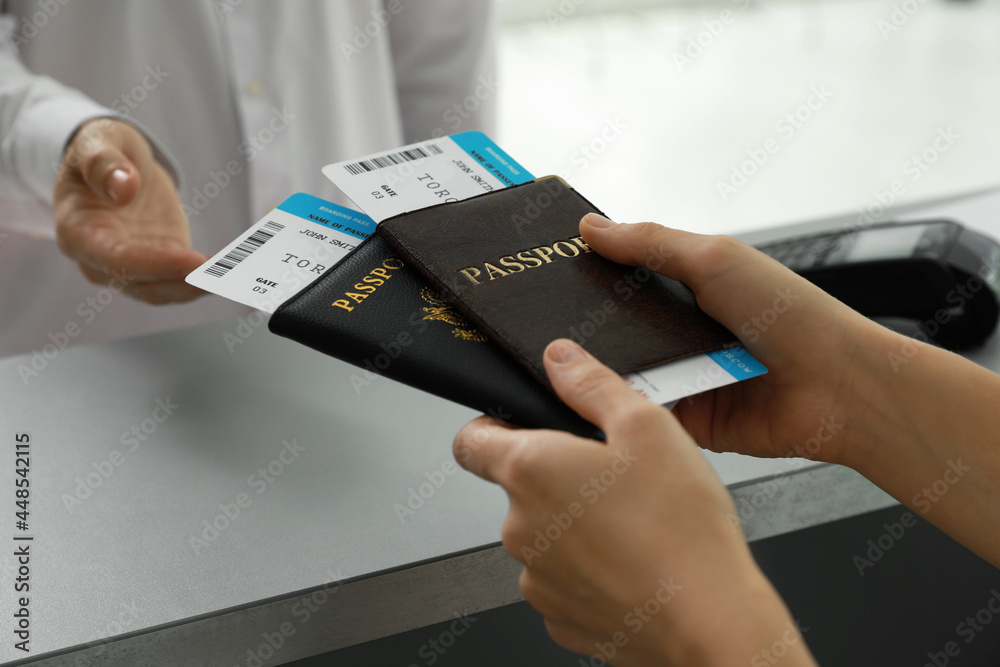 Agent giving passports and tickets to man at check-in desk in airport ...