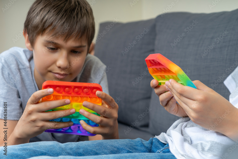 Kids playing with rainbow pop-it fidget toys at home. Push pop it ...