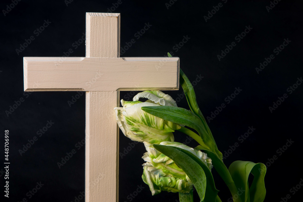 Isolated whithe religious wooden cross with tulip flowers on a dark ...