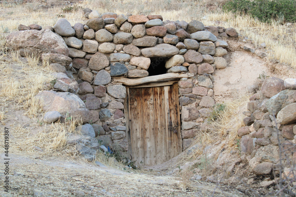 Old stone house facade with battered wooden door. old wooden door on a ...