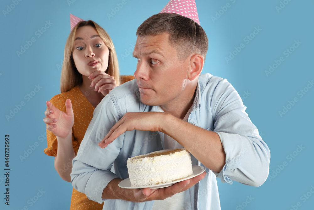 Greedy man hiding birthday cake from woman on turquoise background ...