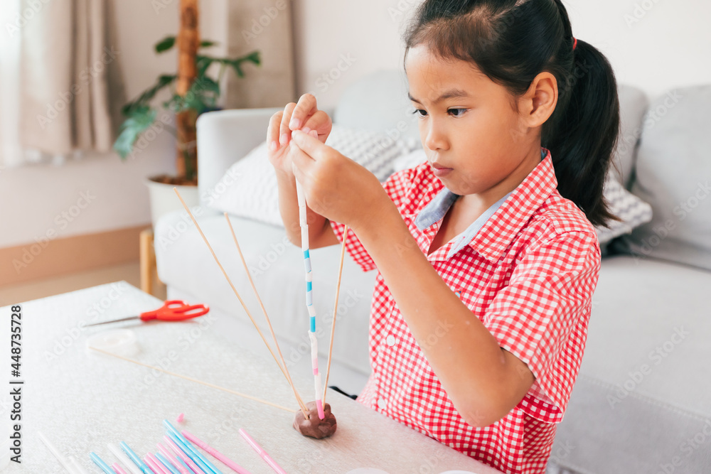 Cute asian child girl playing and creating with playdough and straws ...
