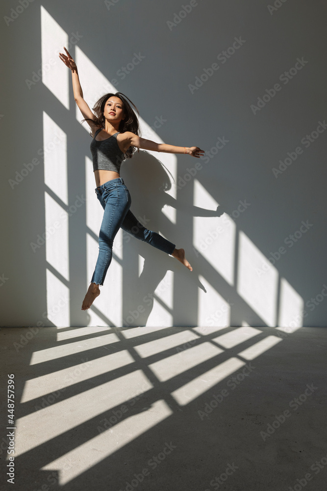 Asian dancer girl makes an acrobatic jump illuminated by the sun that ...