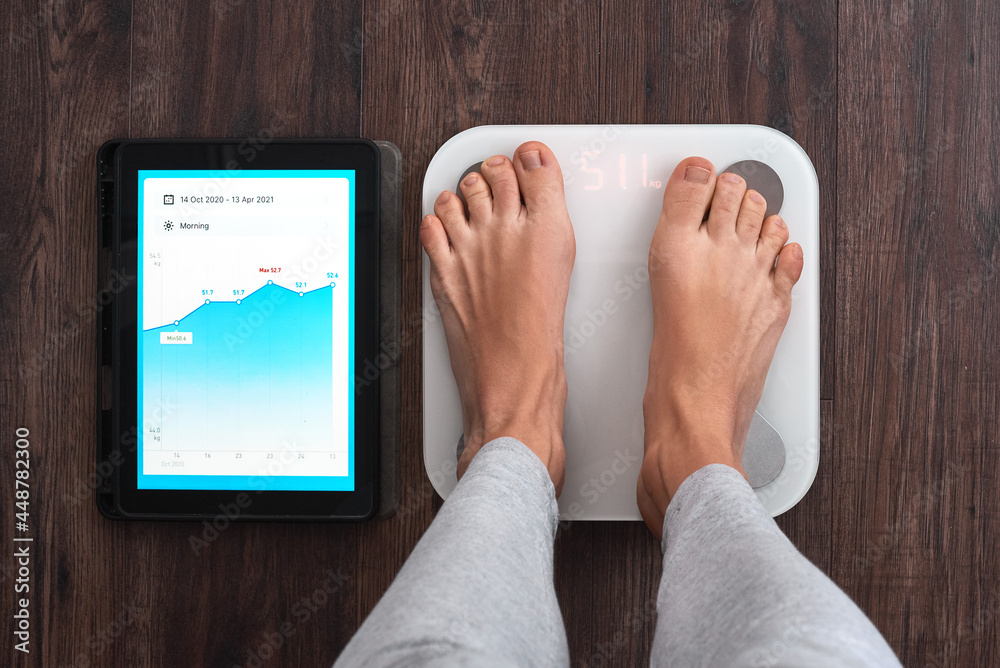 Top View Of a Person Standing On a Smart Weighing Scale and a tablet ...