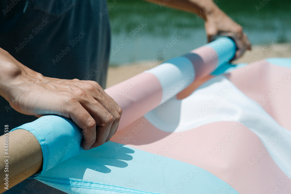 person rolls a transgender pride flag Stock Photo | Adobe Stock
