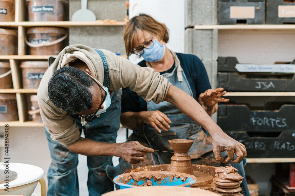 Black potter helping apprentice to cut vase Stock Photo | Adobe Stock