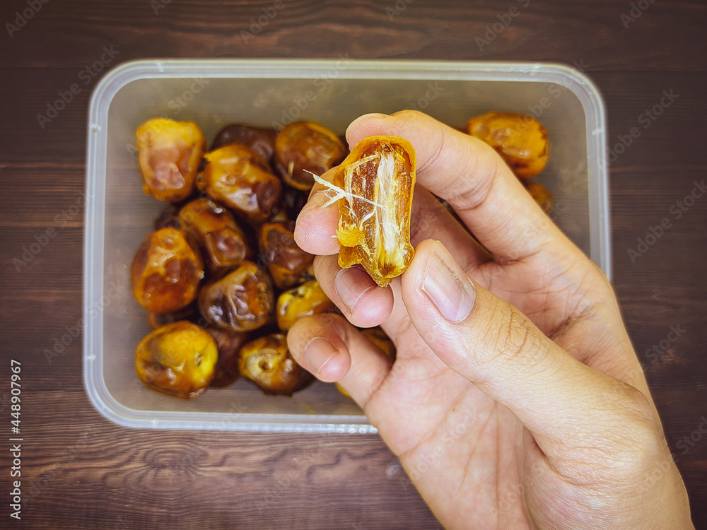 Hand and Fresh brown sukkari dates (kurma sukkari) in plastic box in ...