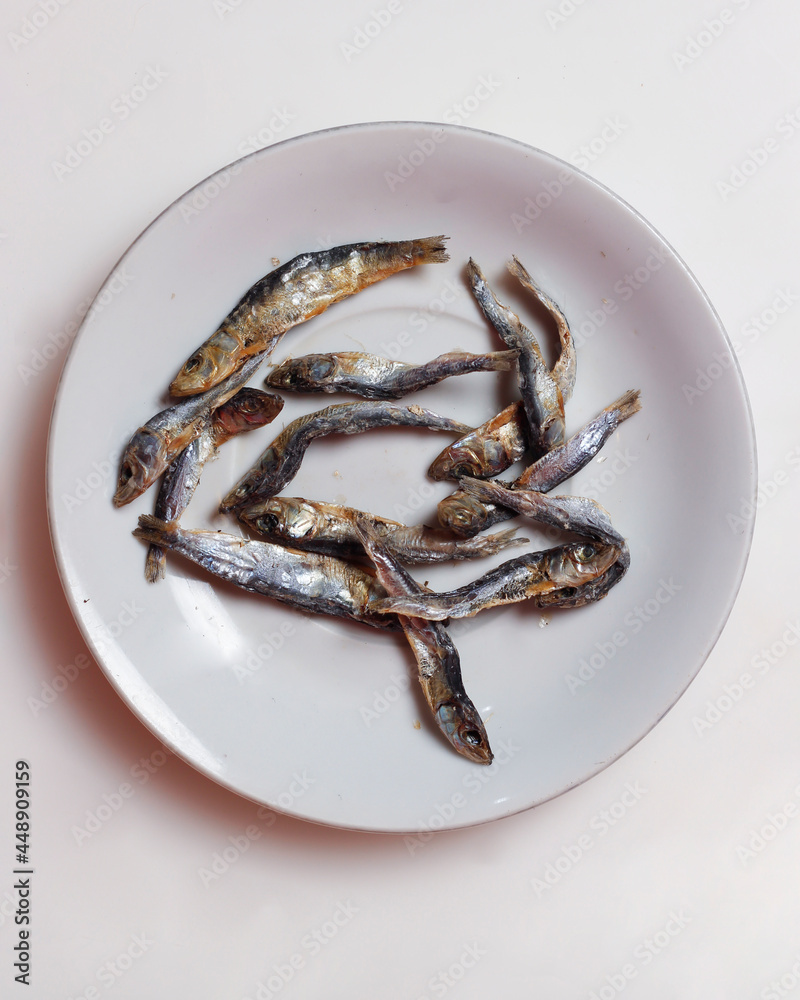 Salted fish isolated on bright background. Process Anchovy is salted in ...