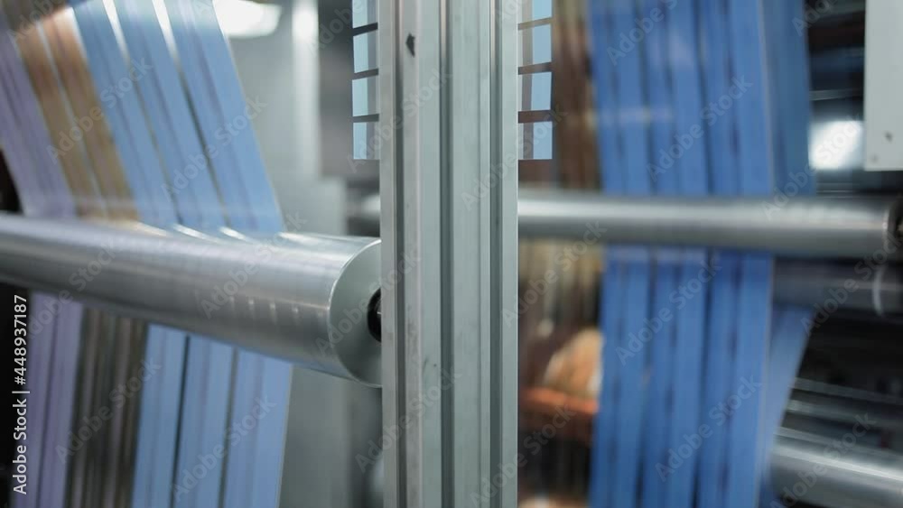 A machine with long metal rollers, along which the plastic packaging ...